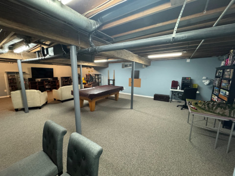 Finished basement with entertainment and table area with chair for ...