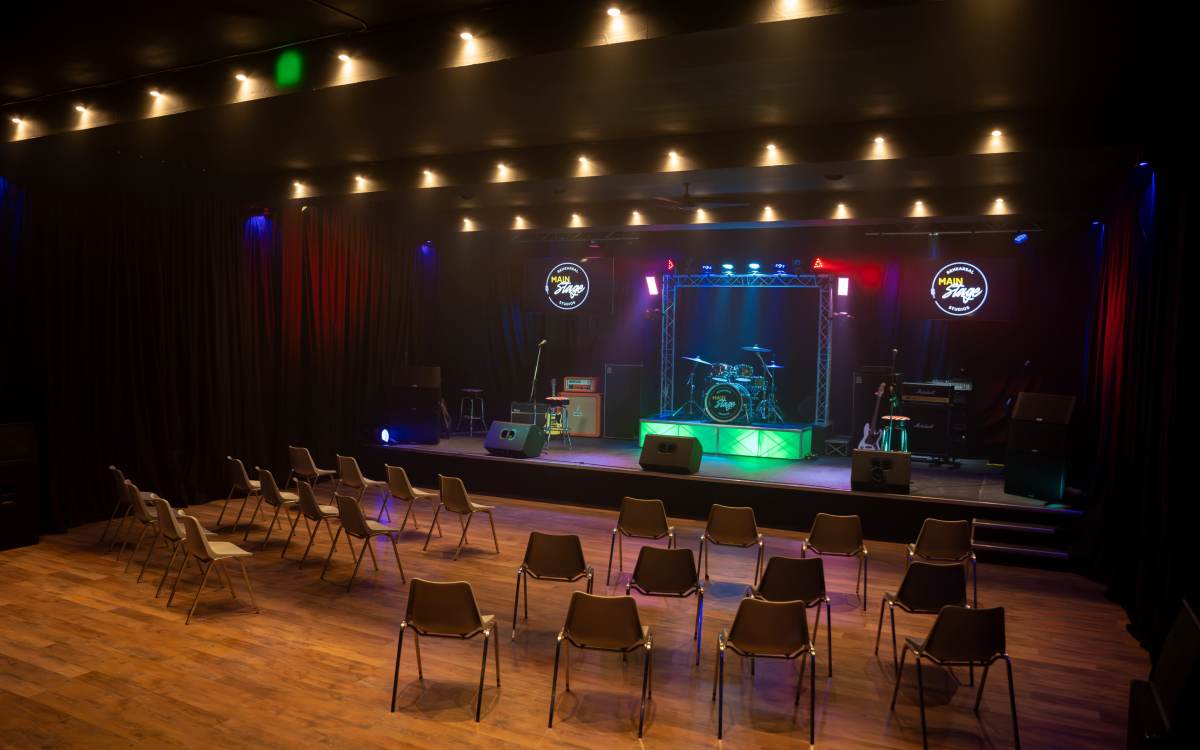Event venue with elevated stage, full backline and stage lighting ...