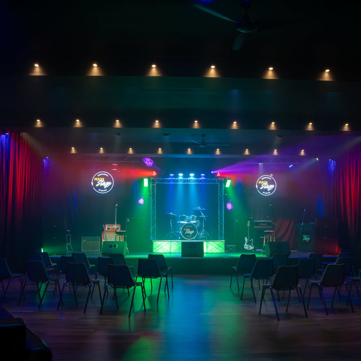 Event venue with elevated stage, full backline and stage lighting ...